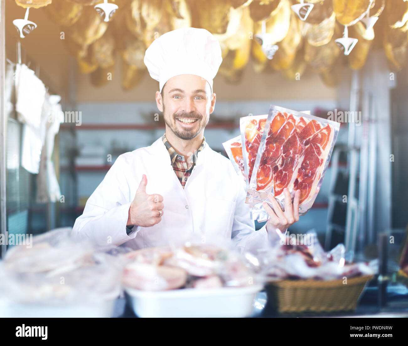 Smiling man seller showing sliced bacon in butcher’s shop Stock Photo ... Smiling man seller showing sliced bacon in butcher’s shop Stock Photo ...
