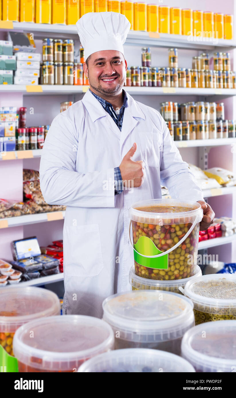 happy russian shop staff standing near containers with olives in ...