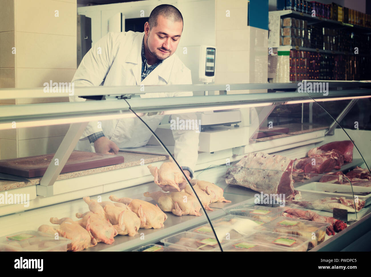 Happy salesman near scales and display with cooled chicken Stock Photo ...