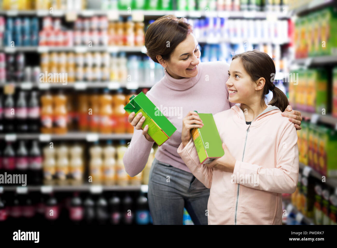 Glad young woman customer with girl looking for refreshing beverages in ...