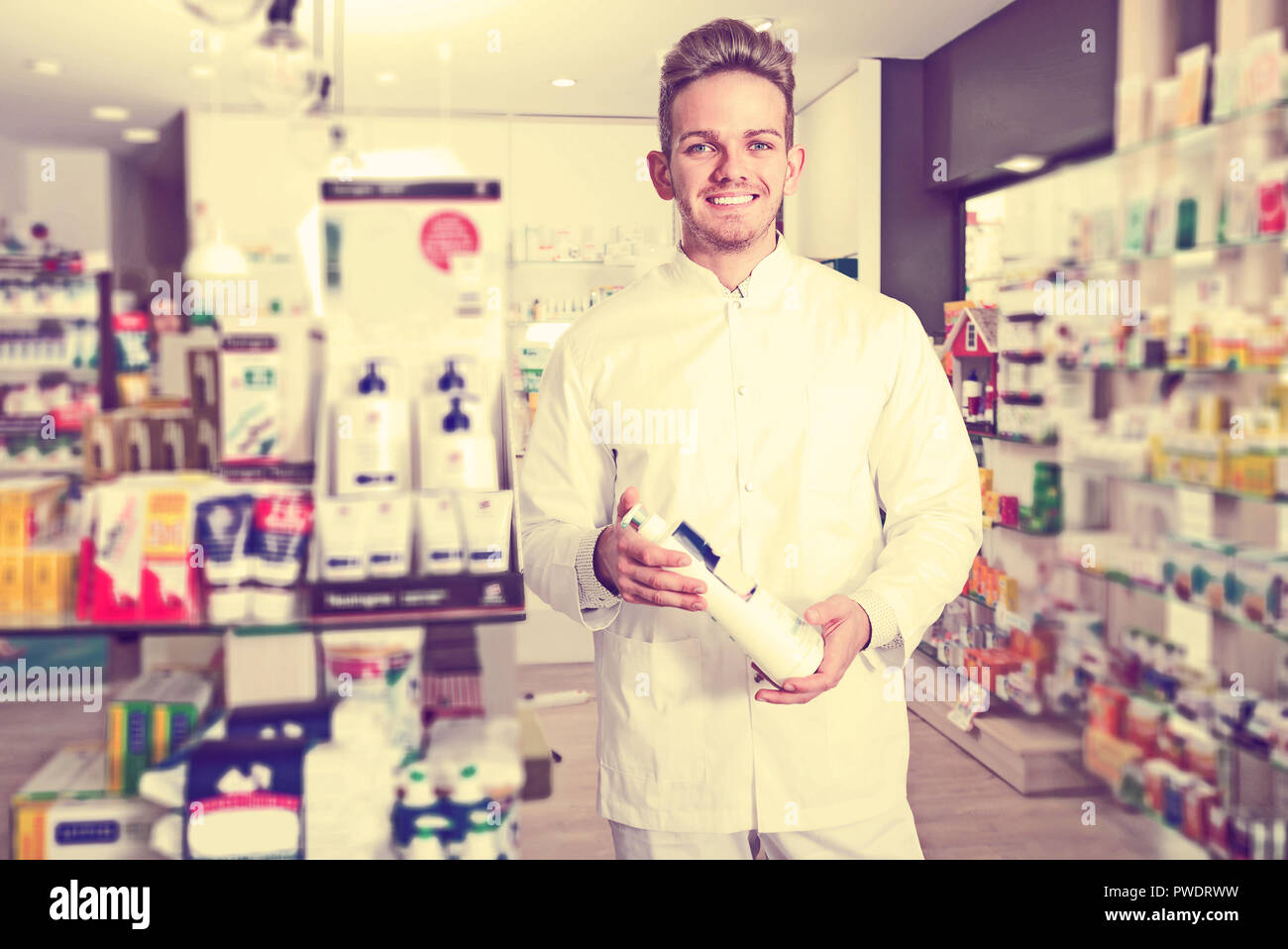 smiling young pharmacist wearing uniform and working in pharmaceutical ...