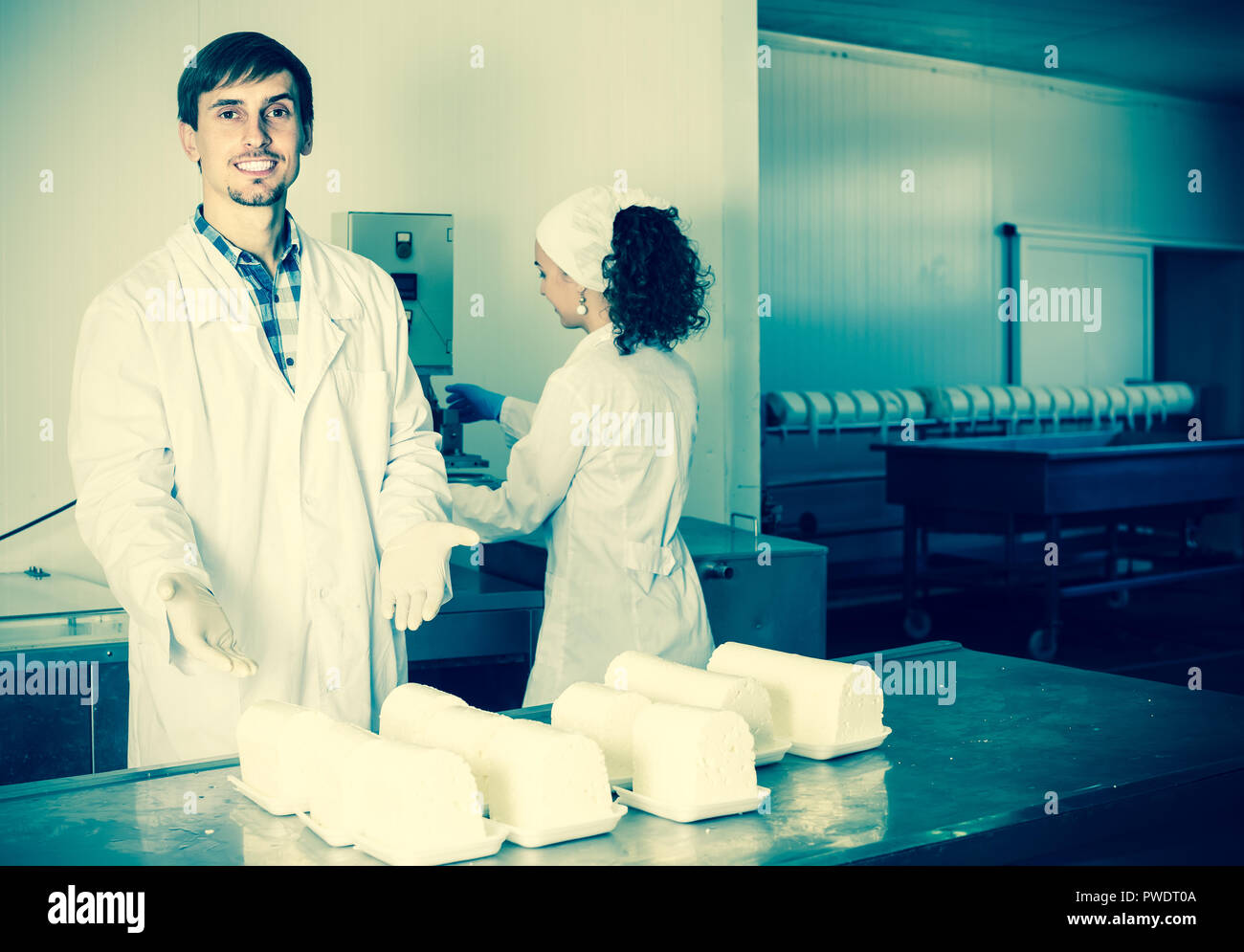 Two joyful young technologists in lab coats during production process ...
