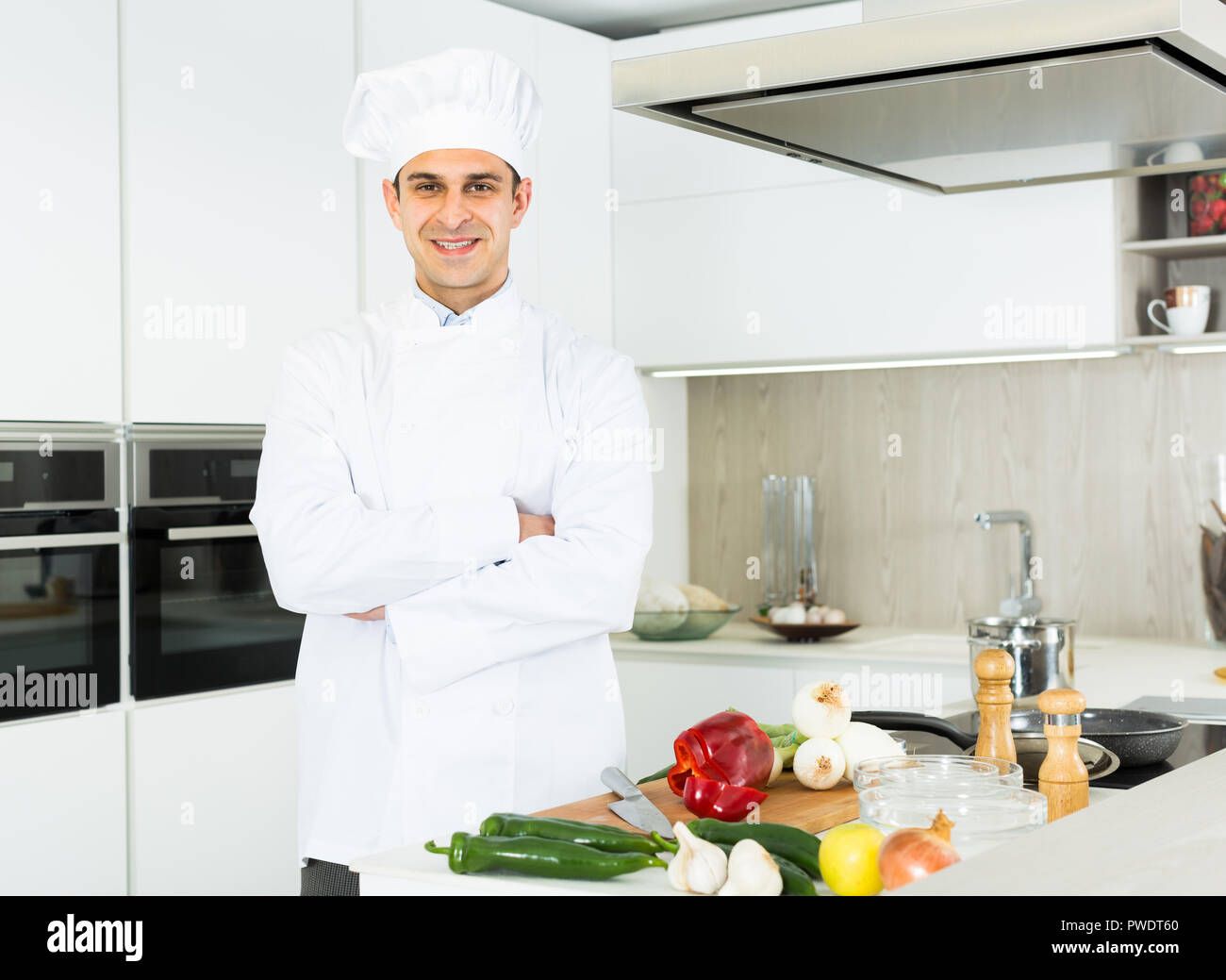 Smiling male kitchener in uniform is standing in the kitchen at the ...