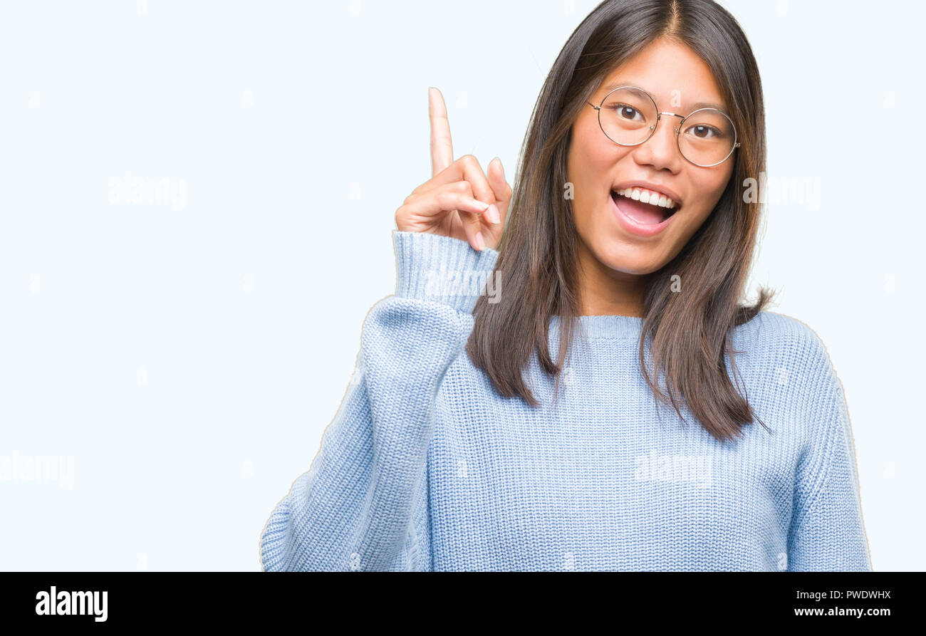 Young asian woman wearing winter sweater over isolated background ...