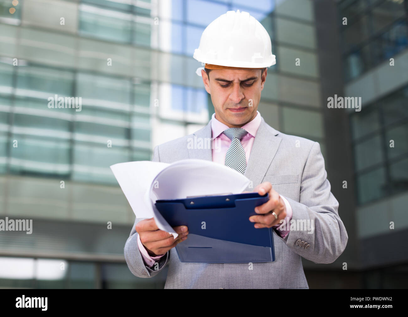 Successful serious manager of large plant reading papers outdoor Stock ...