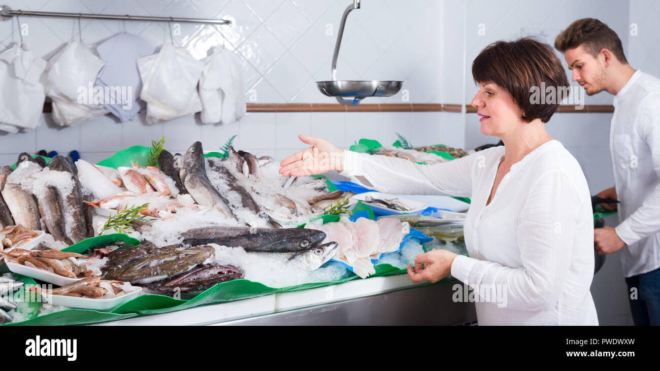 Positive female customer buying fish and chilled seafood in shop Stock ...