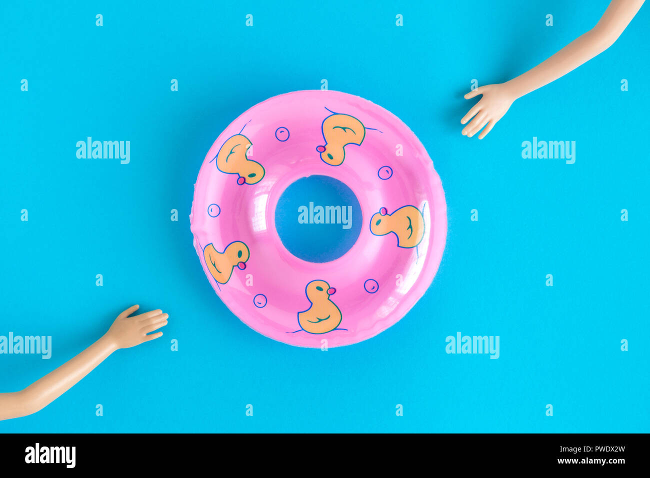 Flat lay of inflatable pool float toy and two doll hands on blue ...