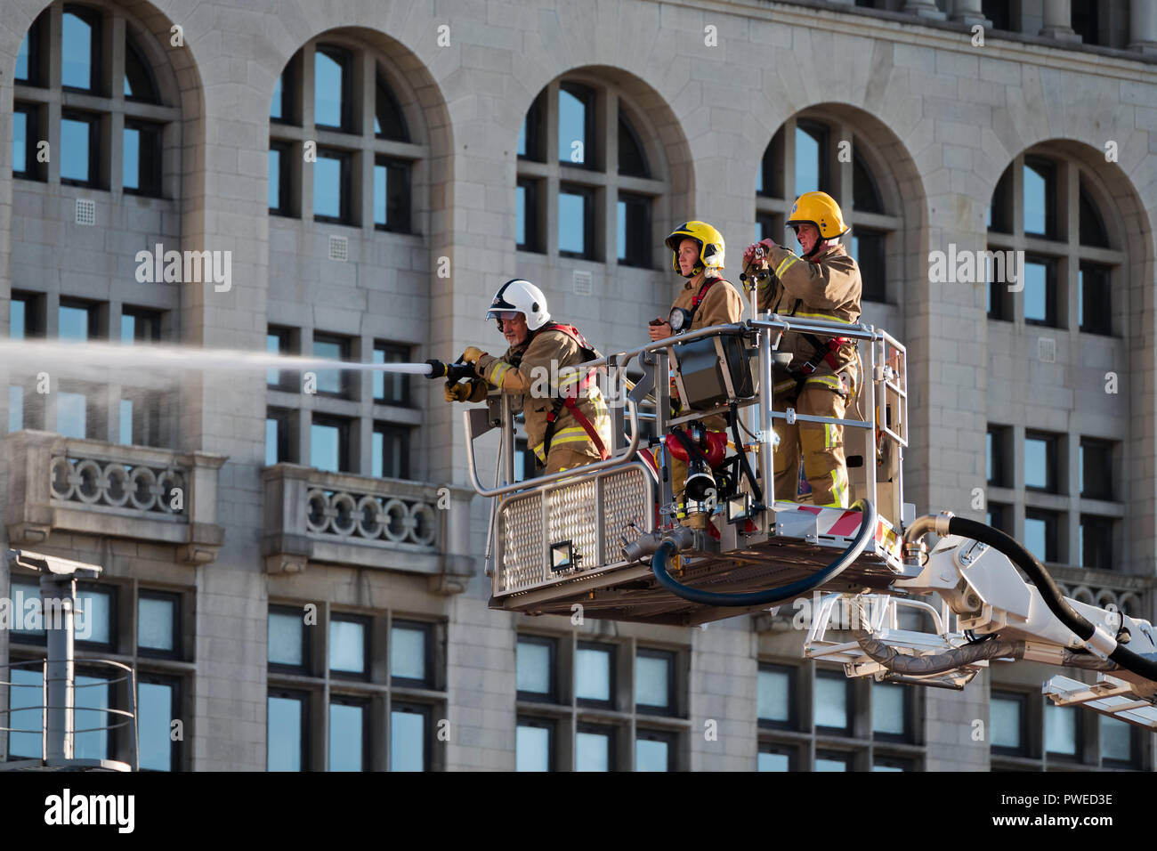 UK firemen using their hose on a high turntable ladder Stock Photo - Alamy