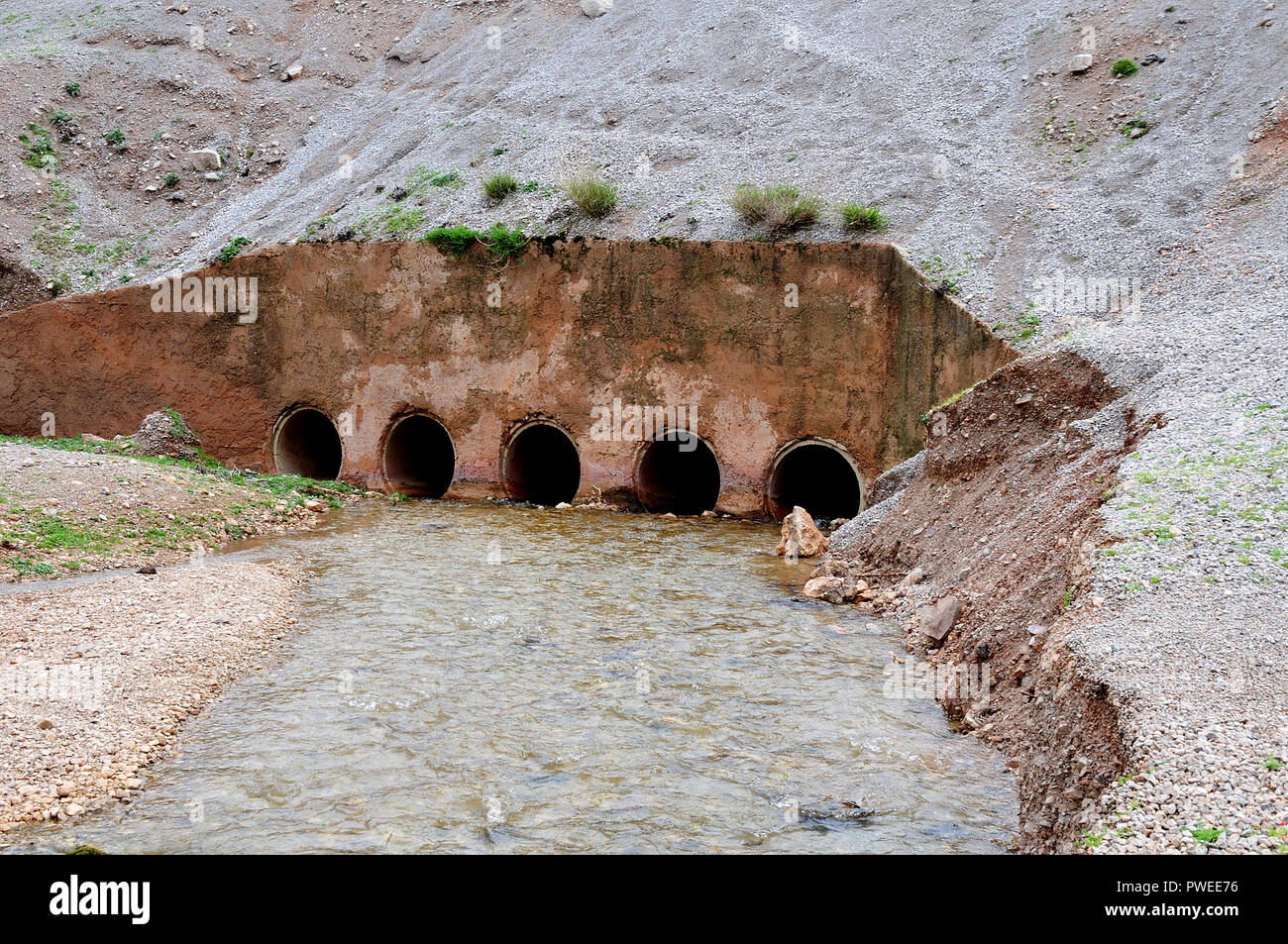 water of a rivulet streaming into tubes under hill in atlas mountains ...