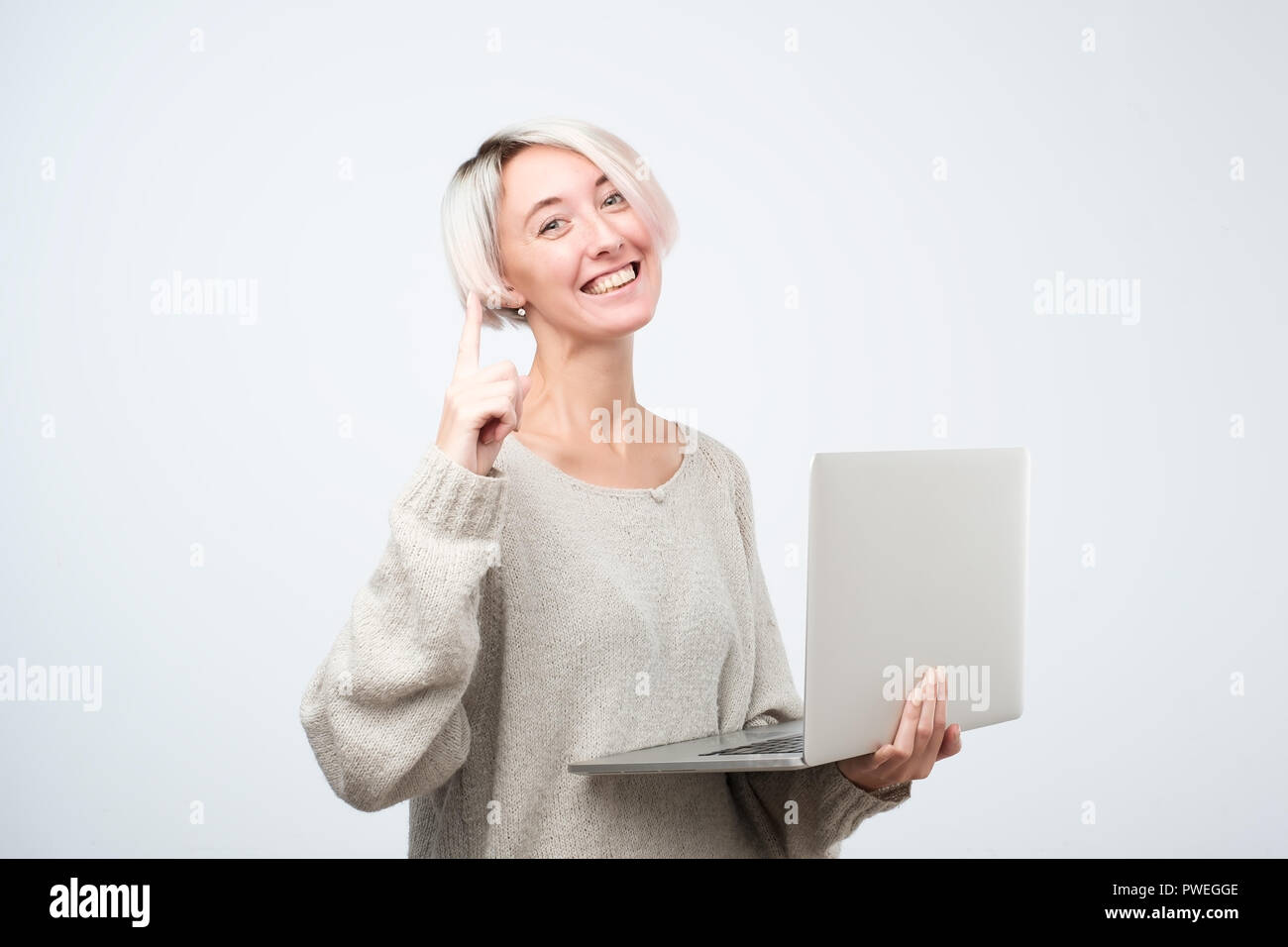Charming happy clever lady is standing with laptop in her hands ...
