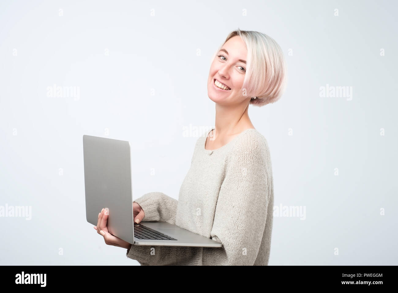 Charming happy clever lady is standing with laptop in her hands ...