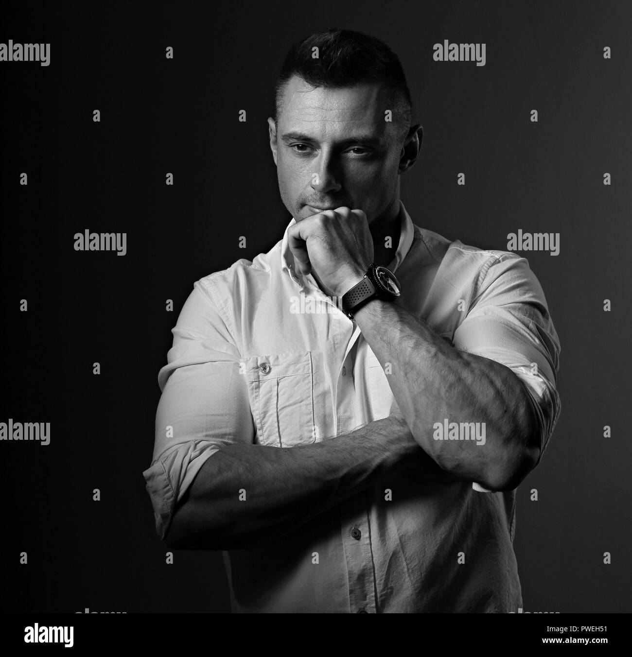 Strong serious business man thinking with sporty biceps arms in white ...