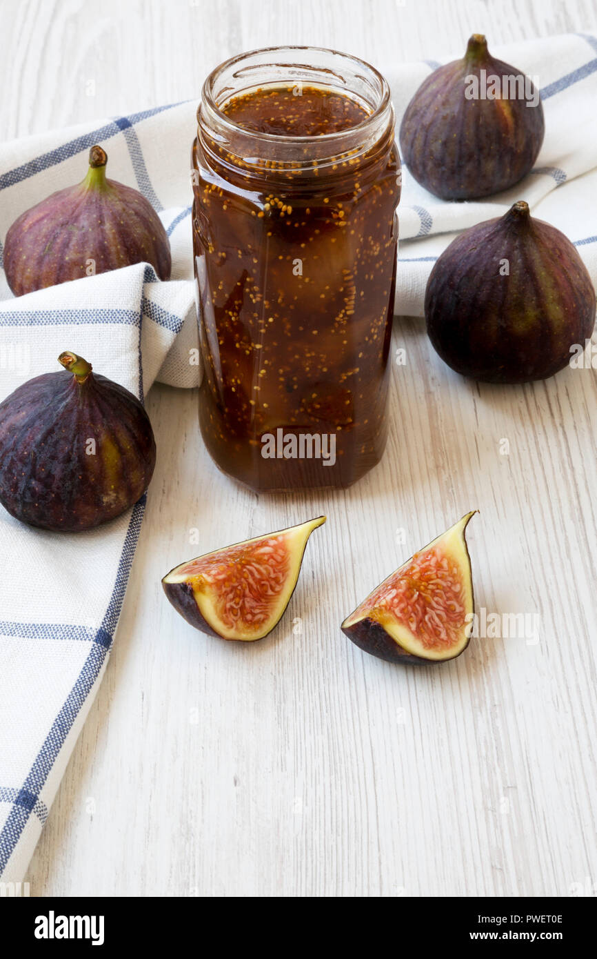 Glass jar of fig jam and fresh figs on white wooden background, side ...