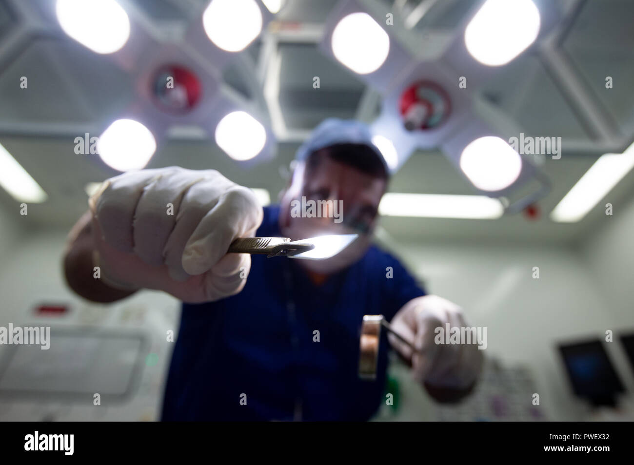 Patient's eye view of a surgeon in an operating theatre with a scalpel ...