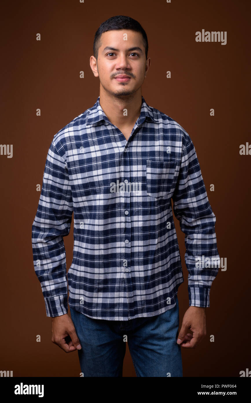 Young multi-ethnic Asian man against brown background Stock Photo - Alamy
