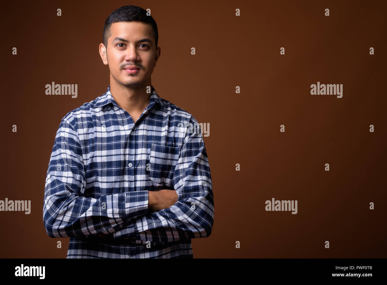 Young multi-ethnic Asian man against brown background Stock Photo - Alamy