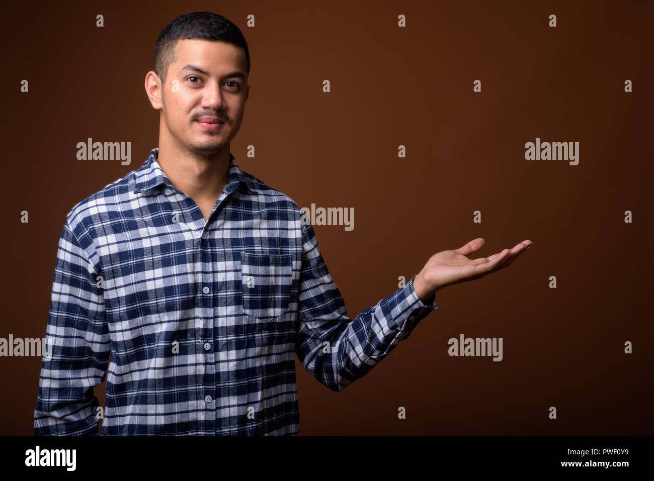 Young multi-ethnic Asian man against brown background Stock Photo - Alamy