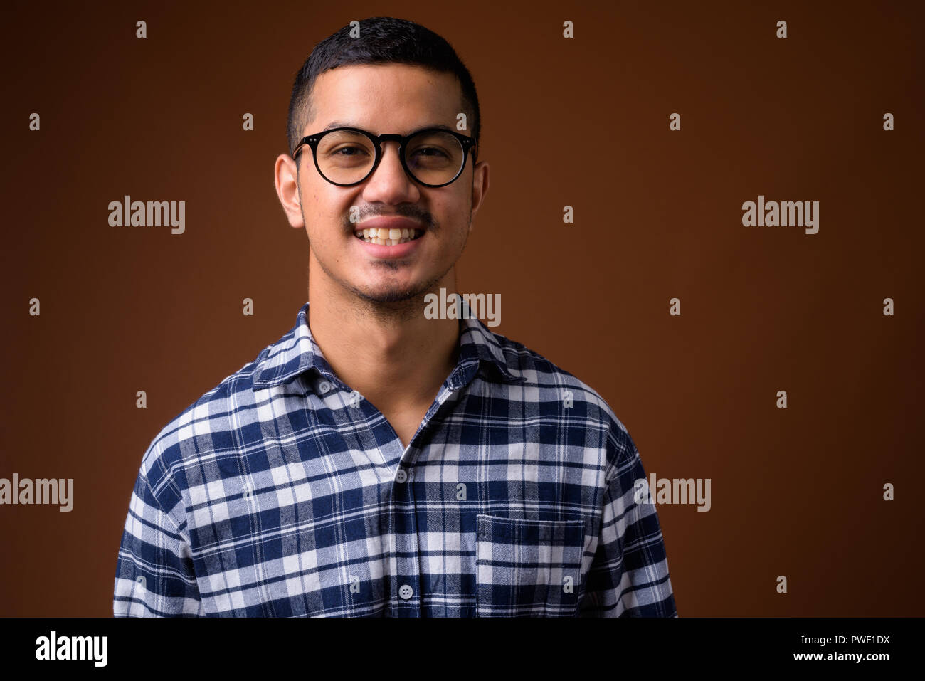 Young multi-ethnic Asian man against brown background Stock Photo - Alamy