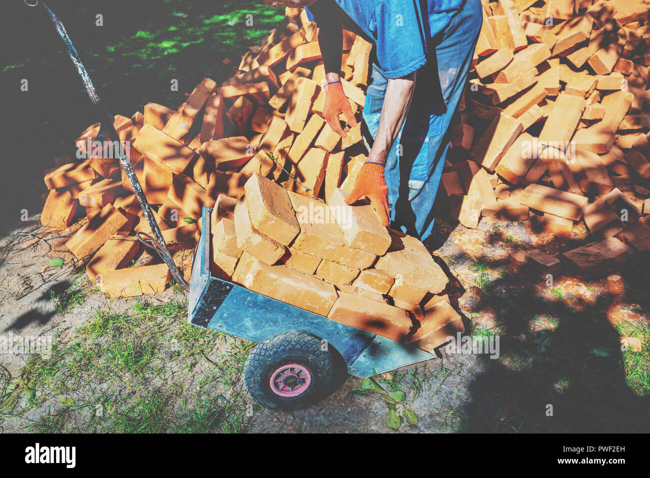 An old man is working at the construction site near the pile of bricks ...