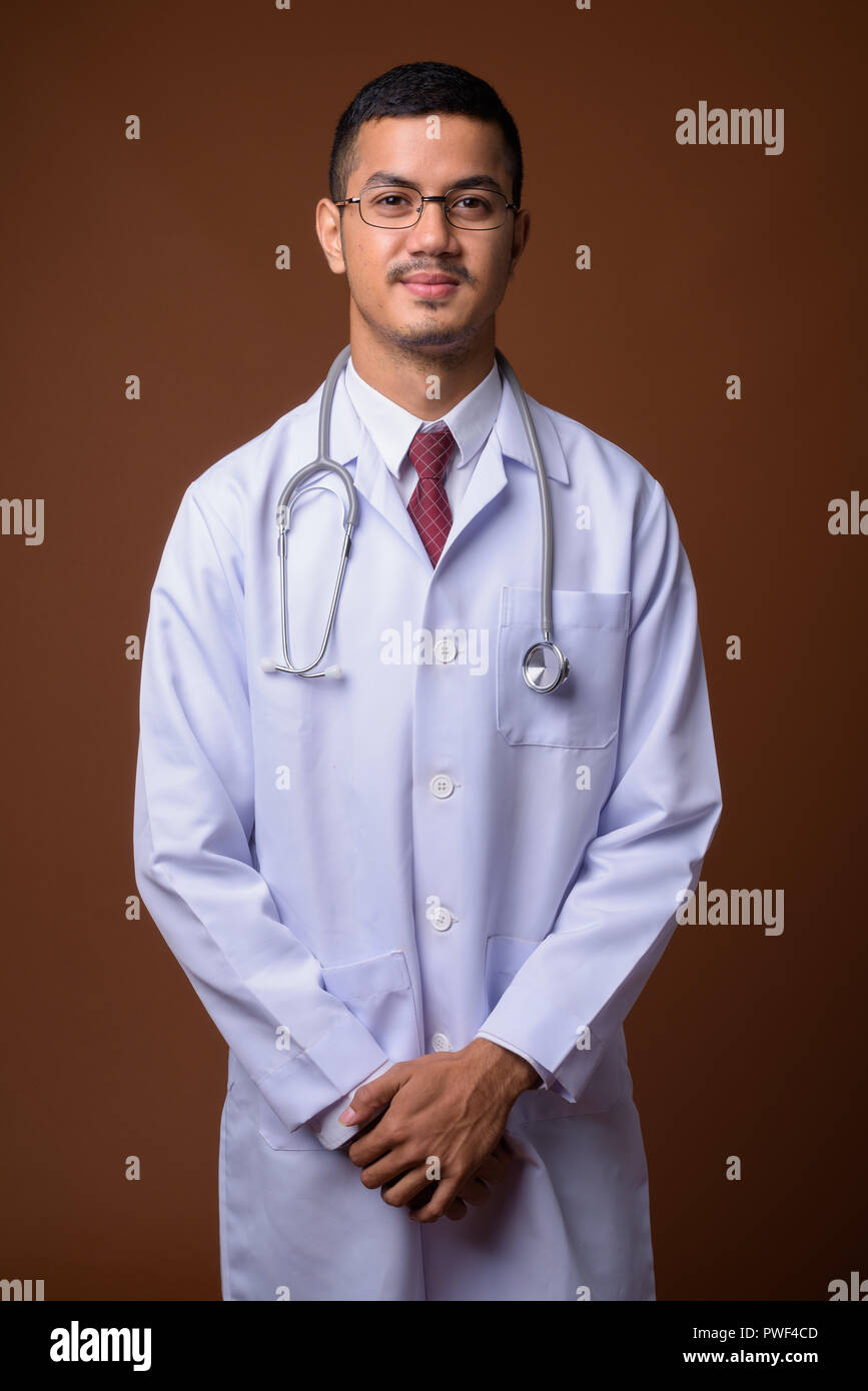 Young multi-ethnic Asian man doctor against brown background Stock ...