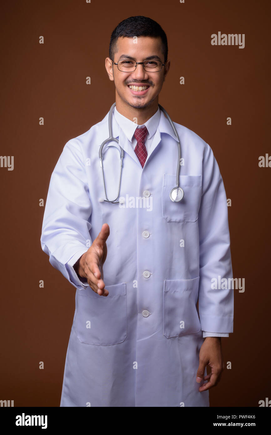 Young multi-ethnic Asian man doctor against brown background Stock ...