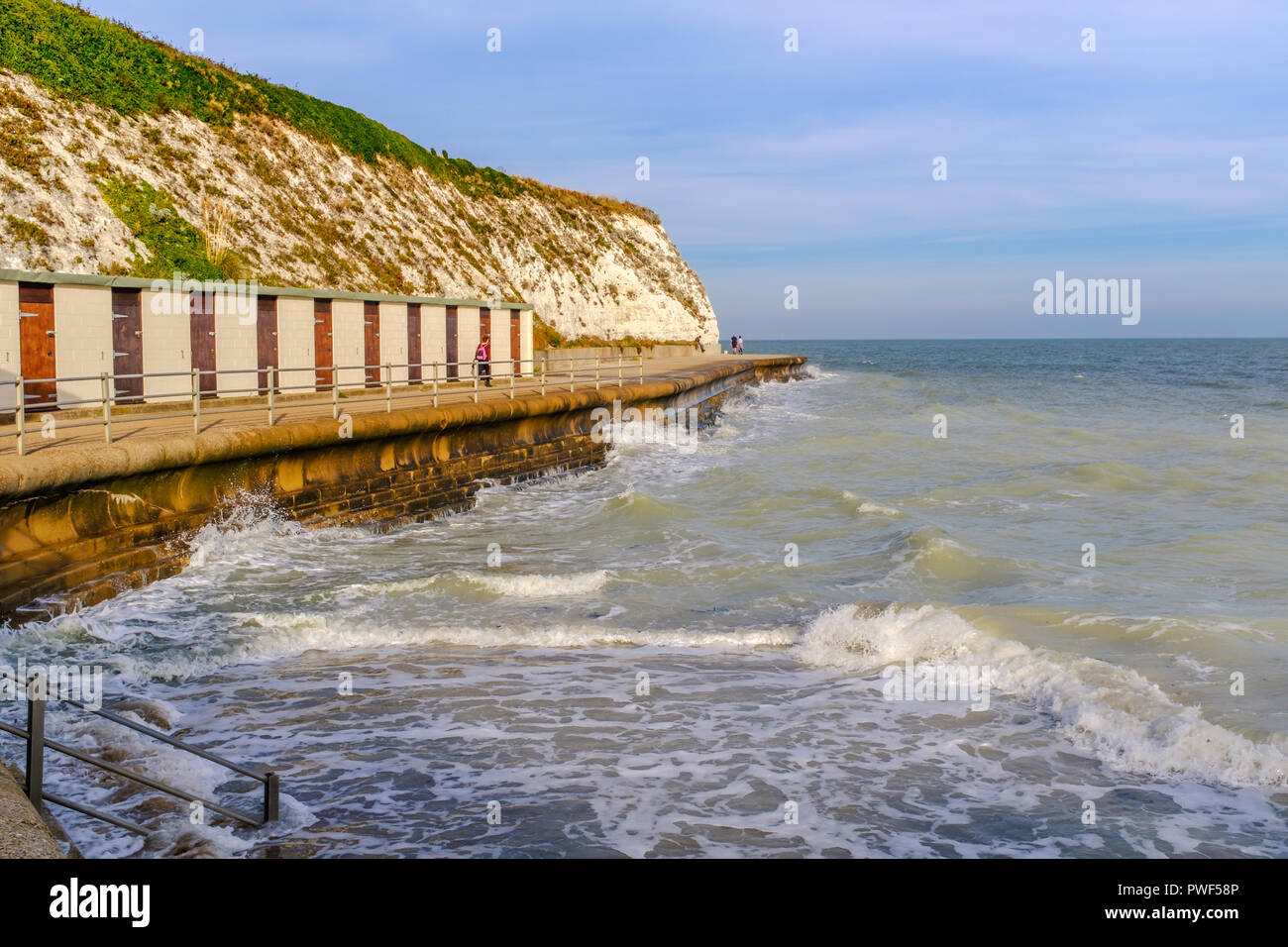 The lower promenade and beach huts along the white chalk cliffs at high ...