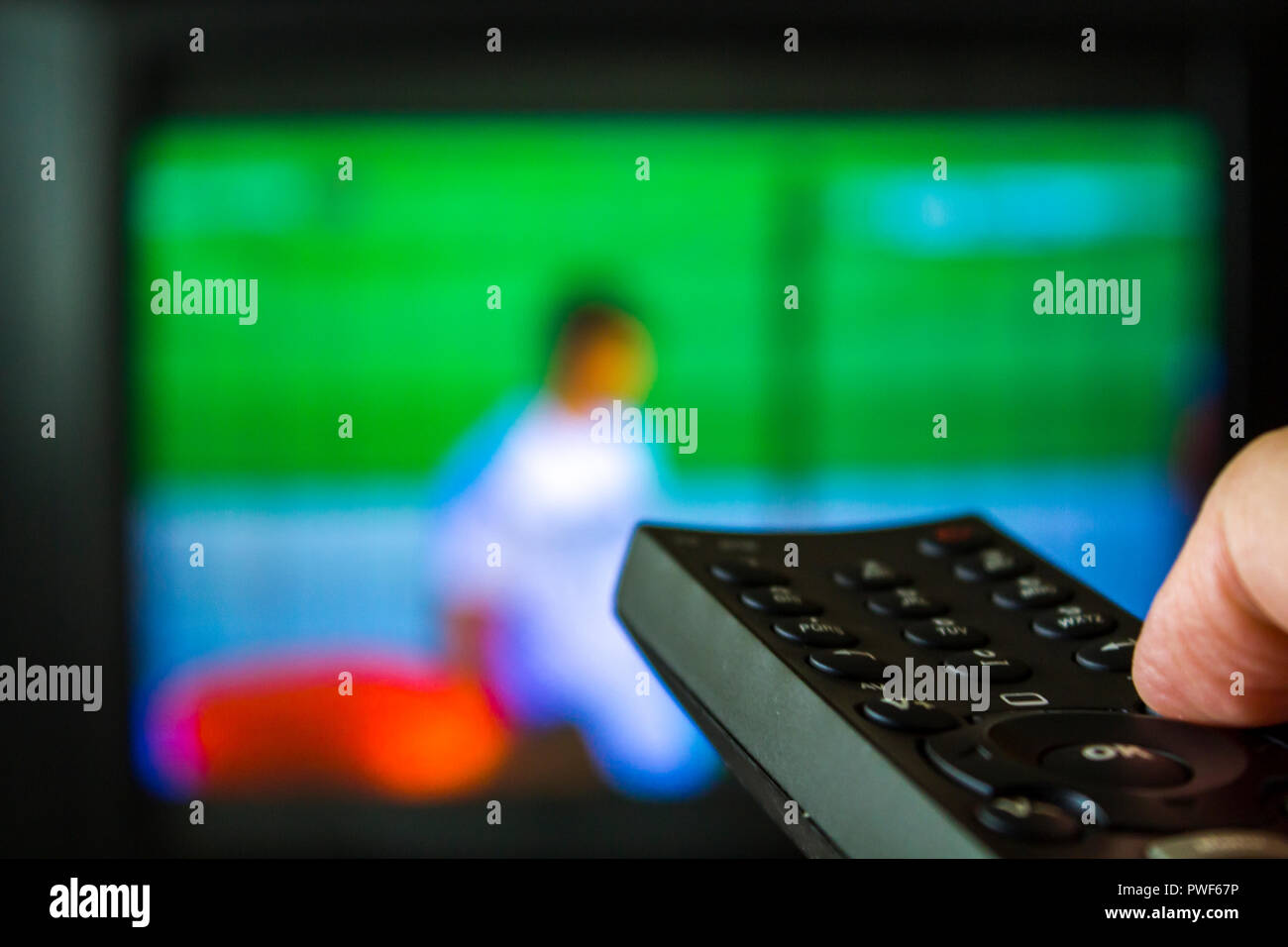 Hand holding TV remote control with tv on the background Stock Photo ...