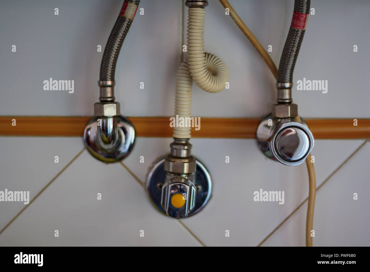 Pipes and water heater faucet on kitchen wall Stock Photo - Alamy