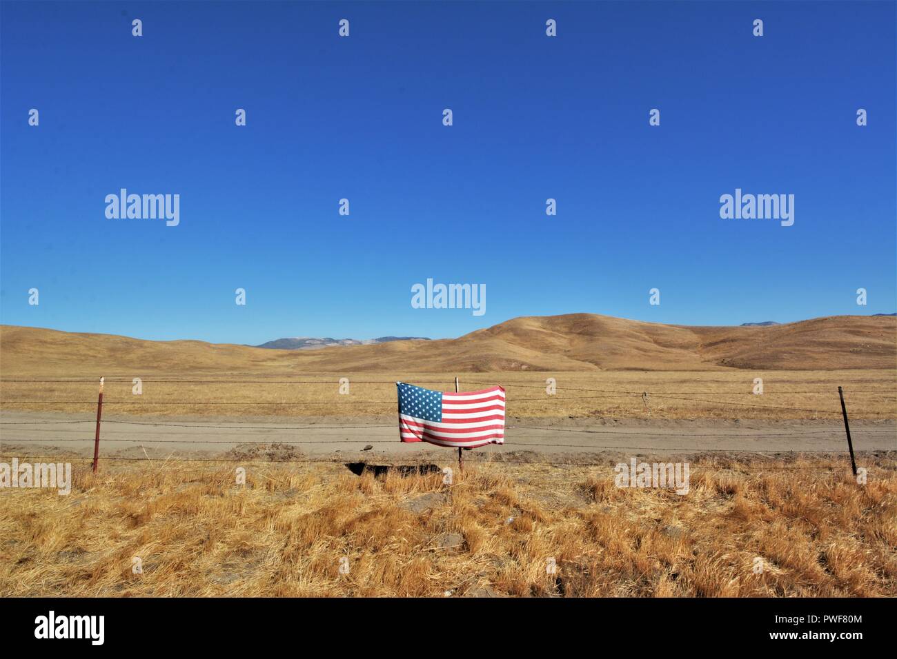 American flag on ranch land barbed wire fence line in high desert of ...