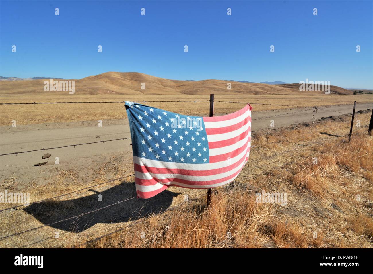 American flag on ranch land barbed wire fence line in high desert of ...