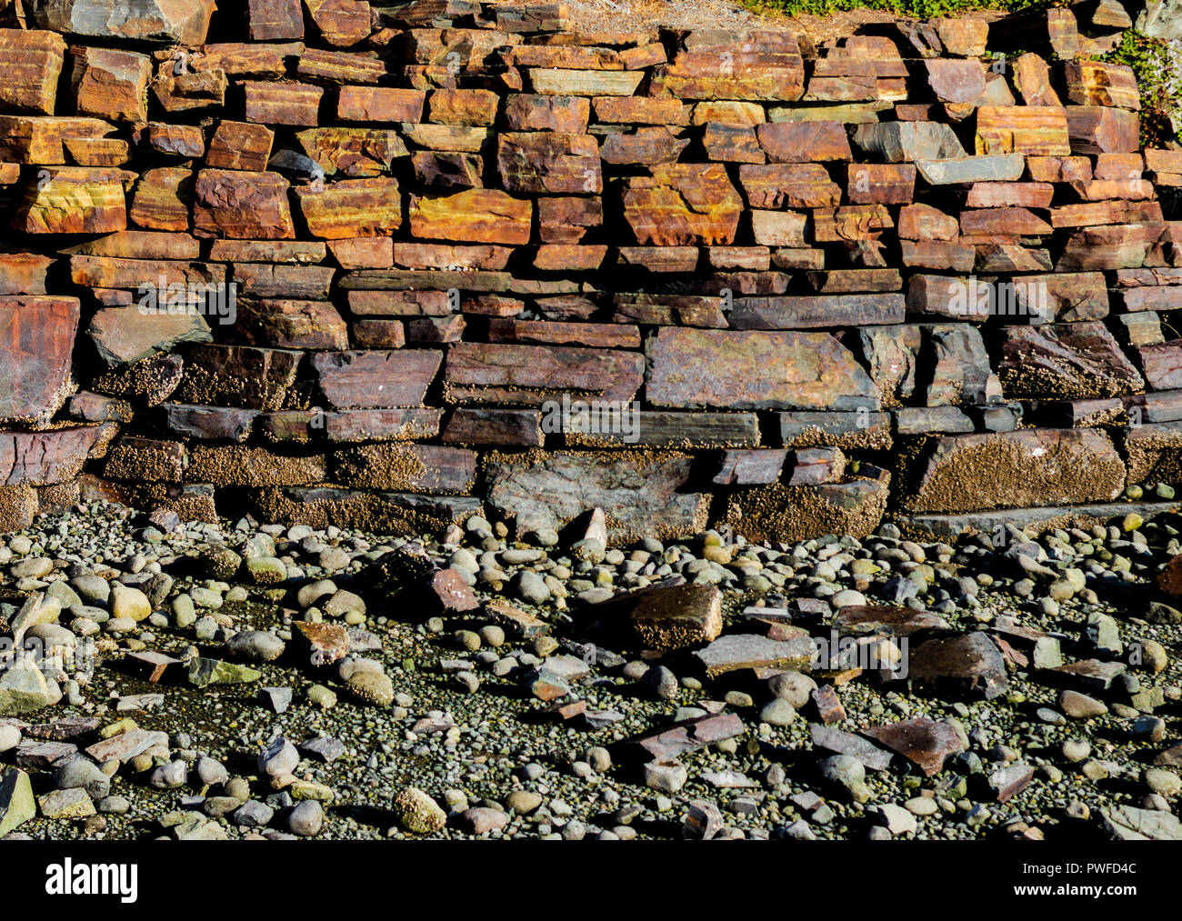 Stacked iron ore stone wall along a rocky beach shoreline Stock Photo ...