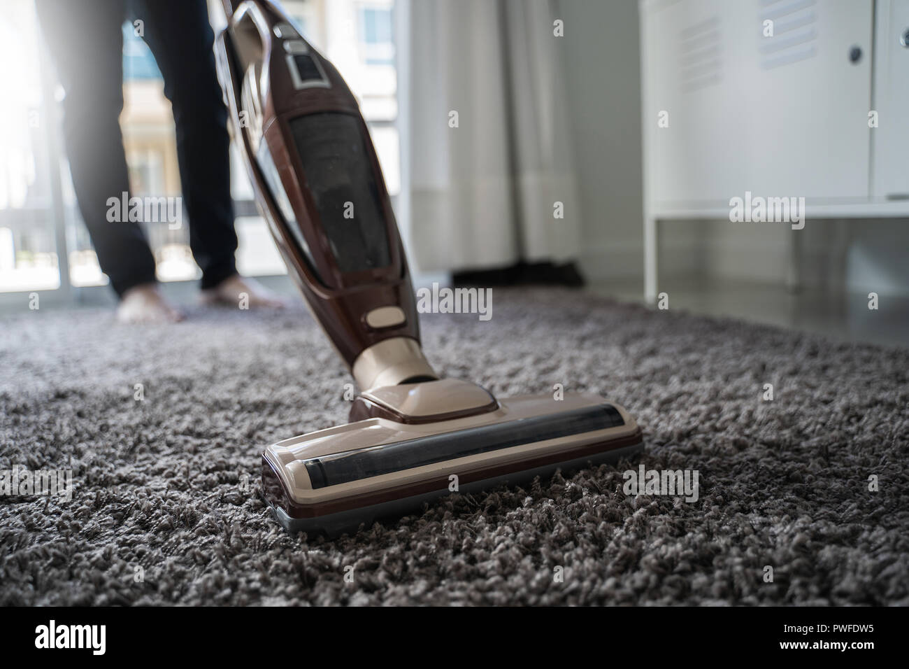 Close-up man using a vacuum cleaner while cleaning in the room Stock ...