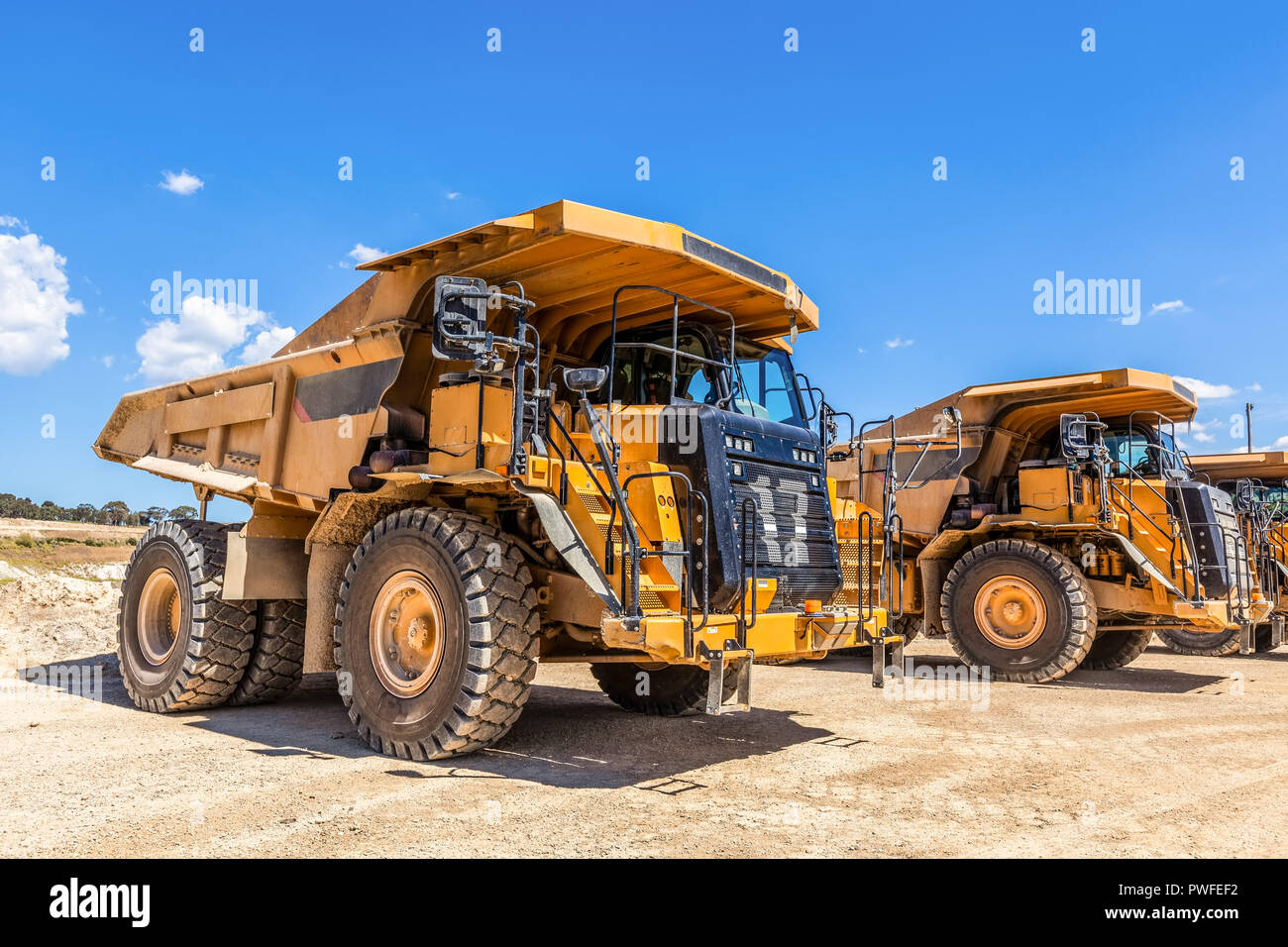 Yellow dumper trucks in a quarry on hot sunny day Stock Photo - Alamy