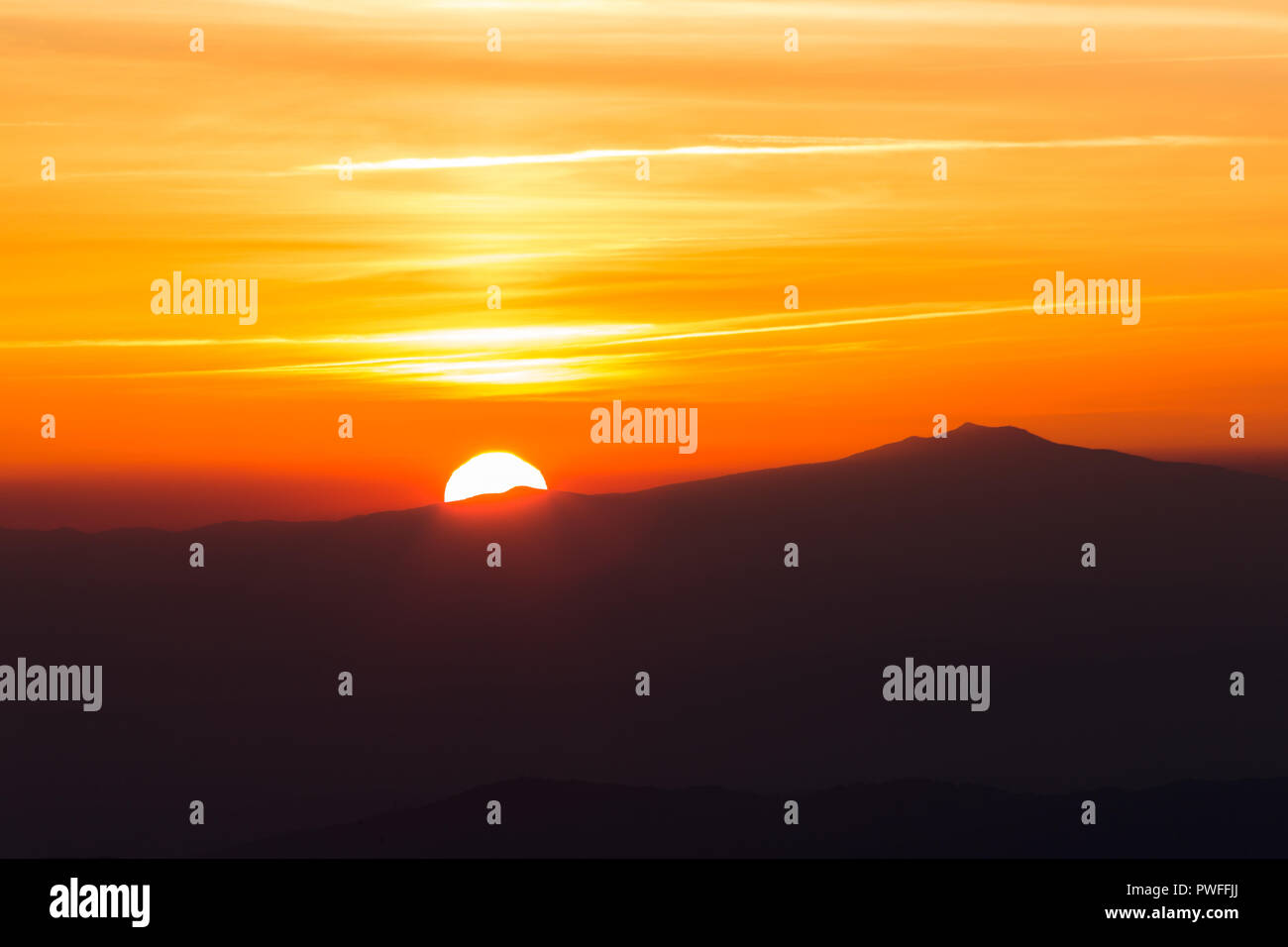 Beautiful sunset with sun coming down behind various layers of ...