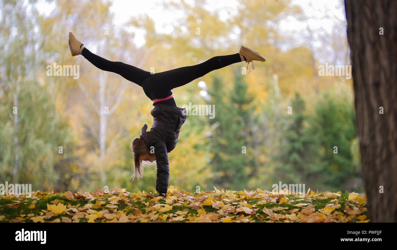 Girl performing gymnast stand on straight hands. Park, autumn Stock ...