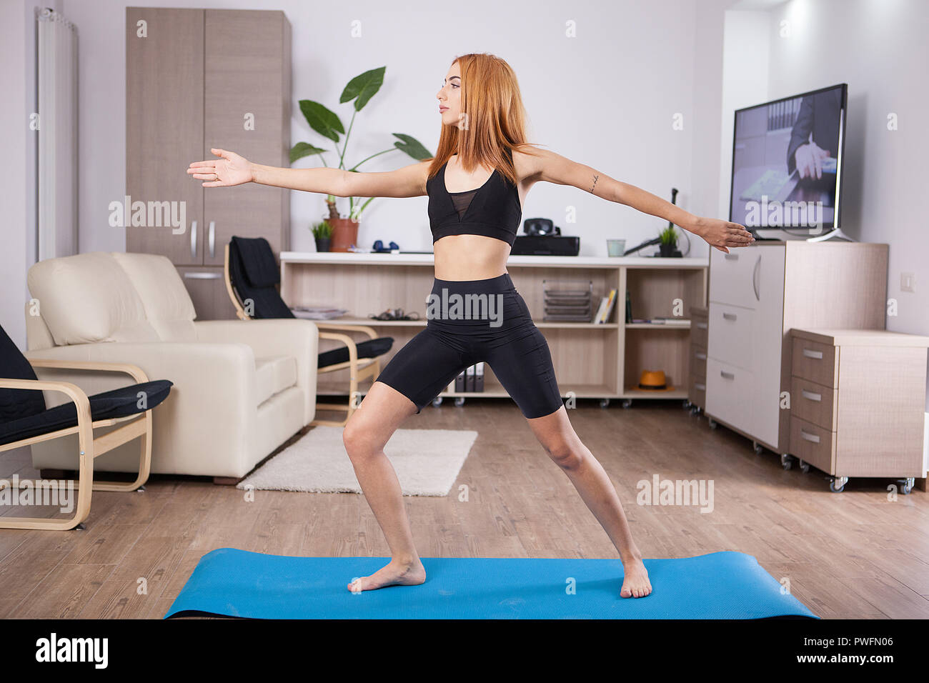 Beautiful young woman staying in Warrior II yoga pose. Home posture ...