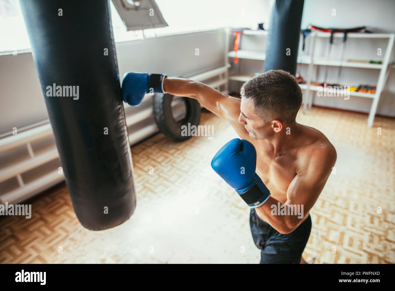 Male boxer hitting punching bag at a boxing studio. Sport training ...