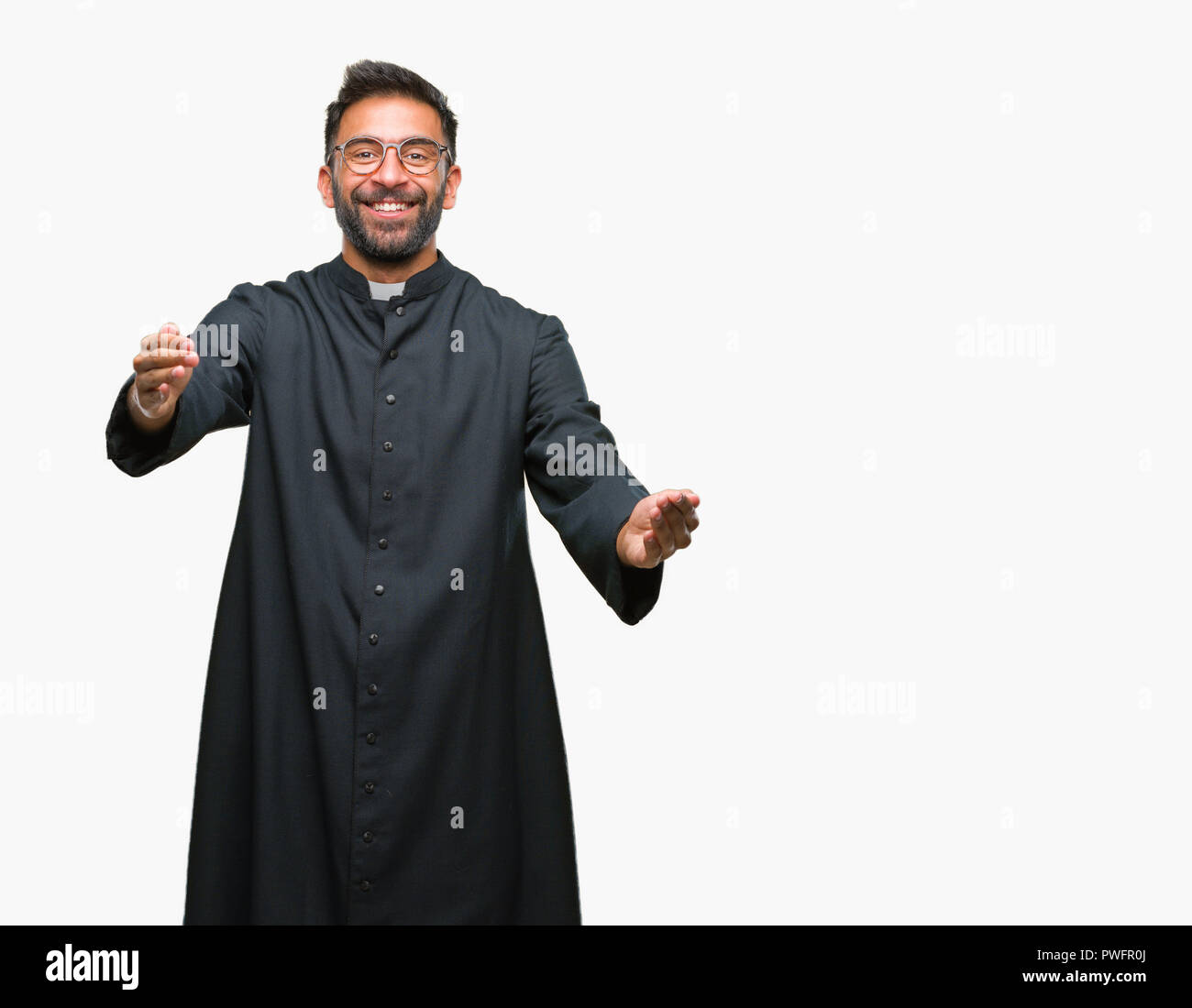 Adult hispanic catholic priest man over isolated background looking at ...