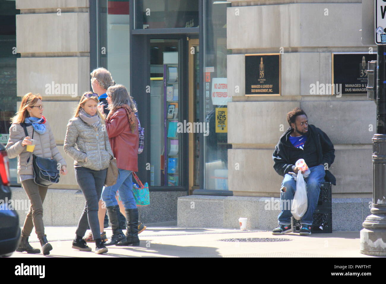 One of many Chicago's homeless people sitting on a milk crate stoop on ...
