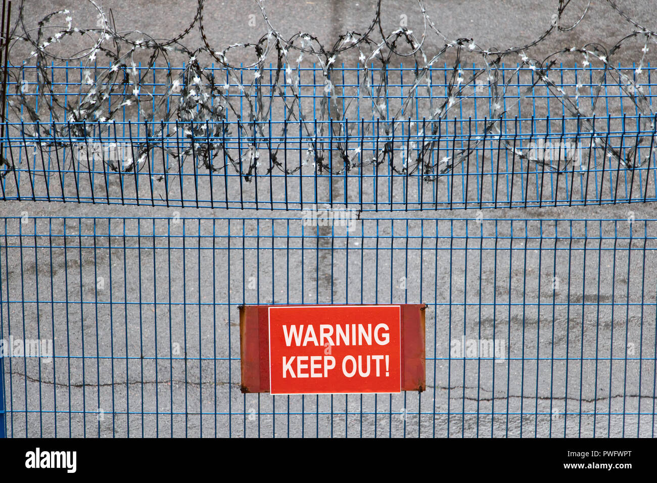 Iron fence with barbed wire. Metallic fence with red warning sign Keep ...