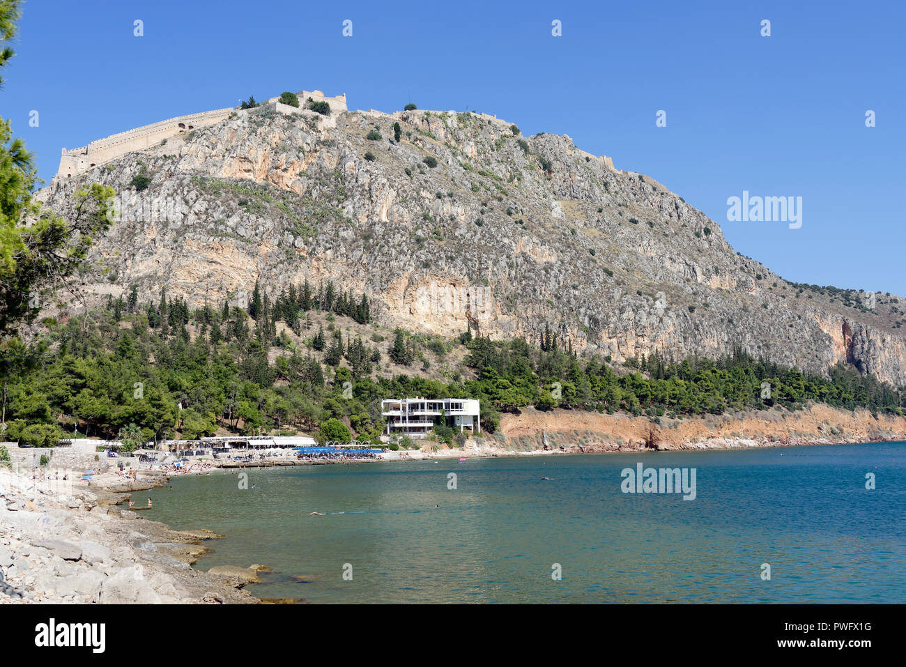 View of the small pebble Arvanitia Beach and the imposing Fortress of ...