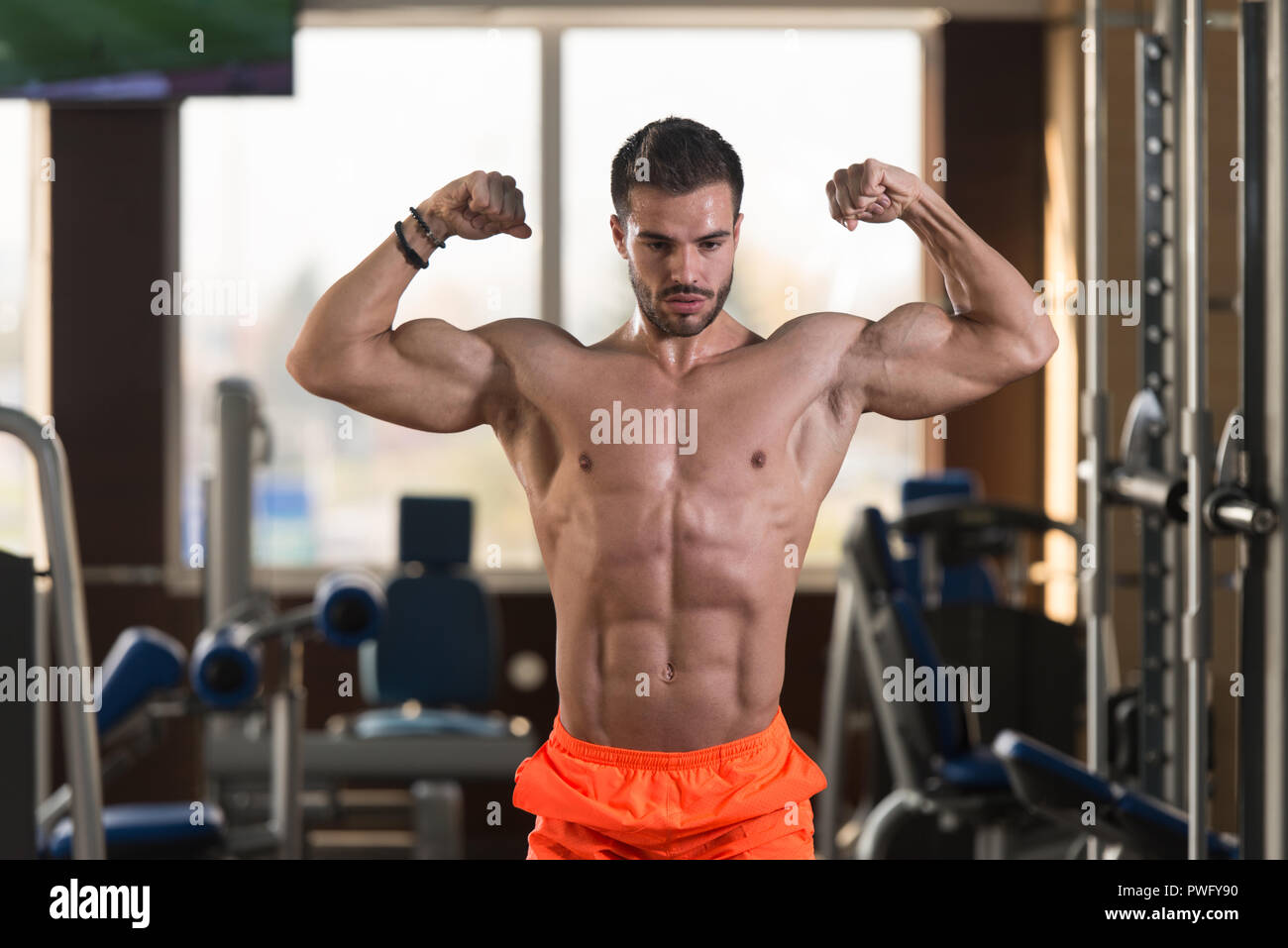 Young Man Standing Strong In The Gym And Flexing Muscles - Muscular Athletic Bodybuilder Fitness ...