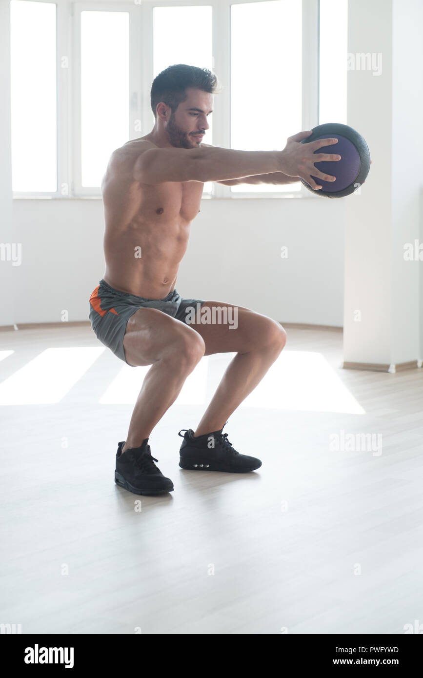 Handsome Young Man Doing Squad With Medicine Ball As Part Of ...
