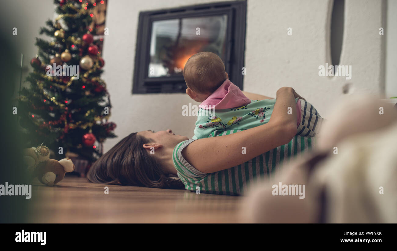 Retro image of young mother lying on the floor in front of a fire place ...
