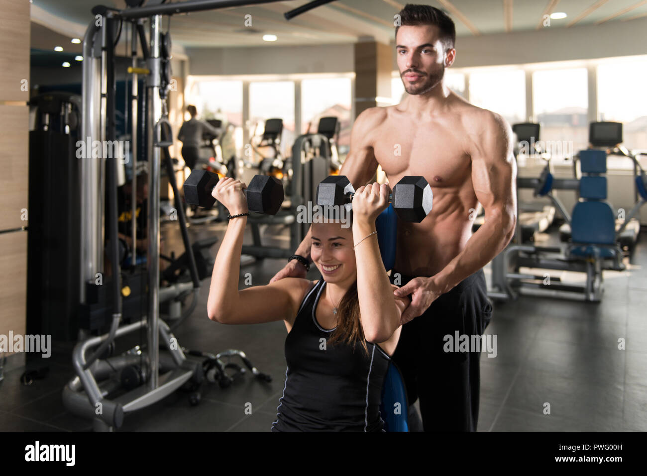 Personal Trainer Showing Young Woman How To Train Shoulders With ...
