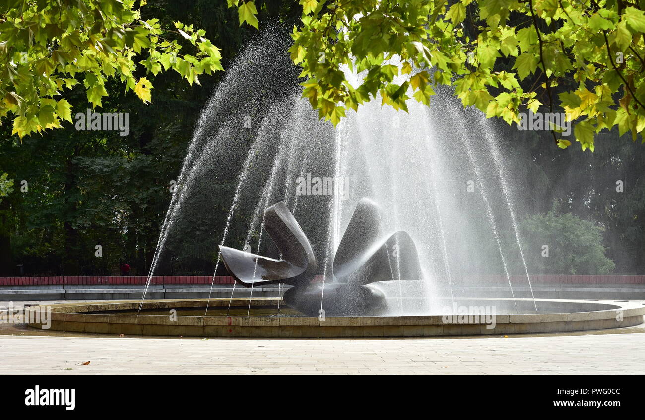 Fountain with bright sunlight reflecting on water drops and spray among ...