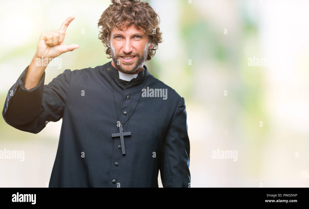 Handsome hispanic catholic priest man over isolated background smiling ...