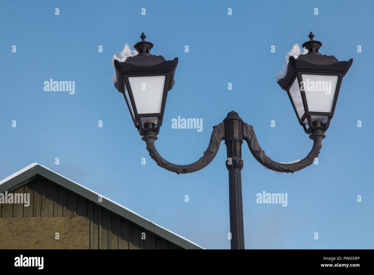 Vintage black street lamppost with two lamps and roof of building ...