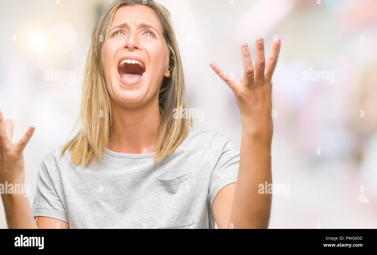 Young beautiful woman over isolated background crazy and mad shouting ...