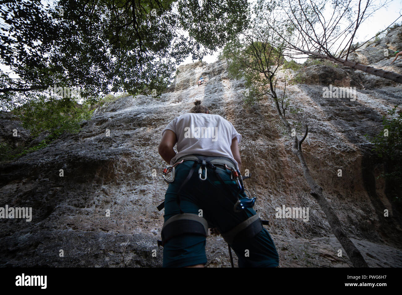 From below of anonymous man in harness looking up at mountain and ...